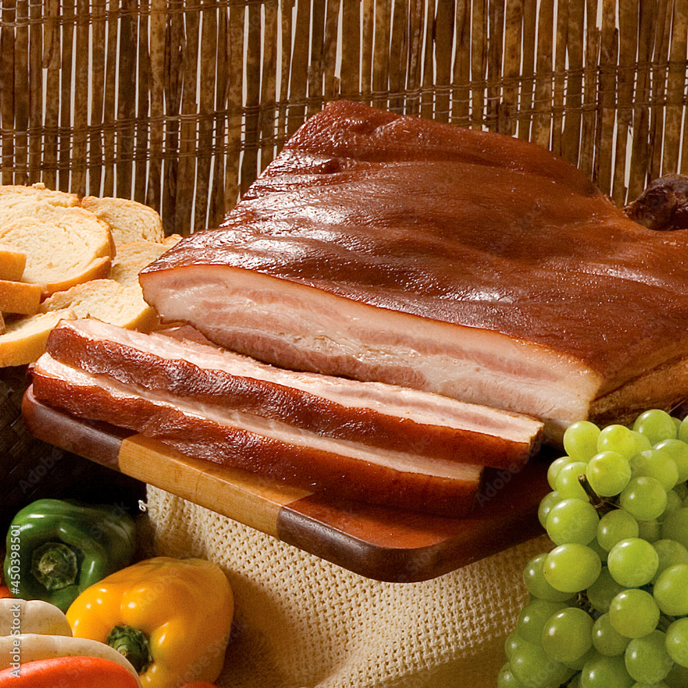 Foto de Bacon defumado inteiro e com fatias em tábua de madeira, com ...