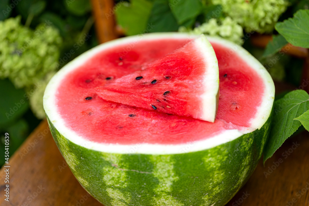 Half of a ripe red watermelon and a triangular slice of juicy ripe ...