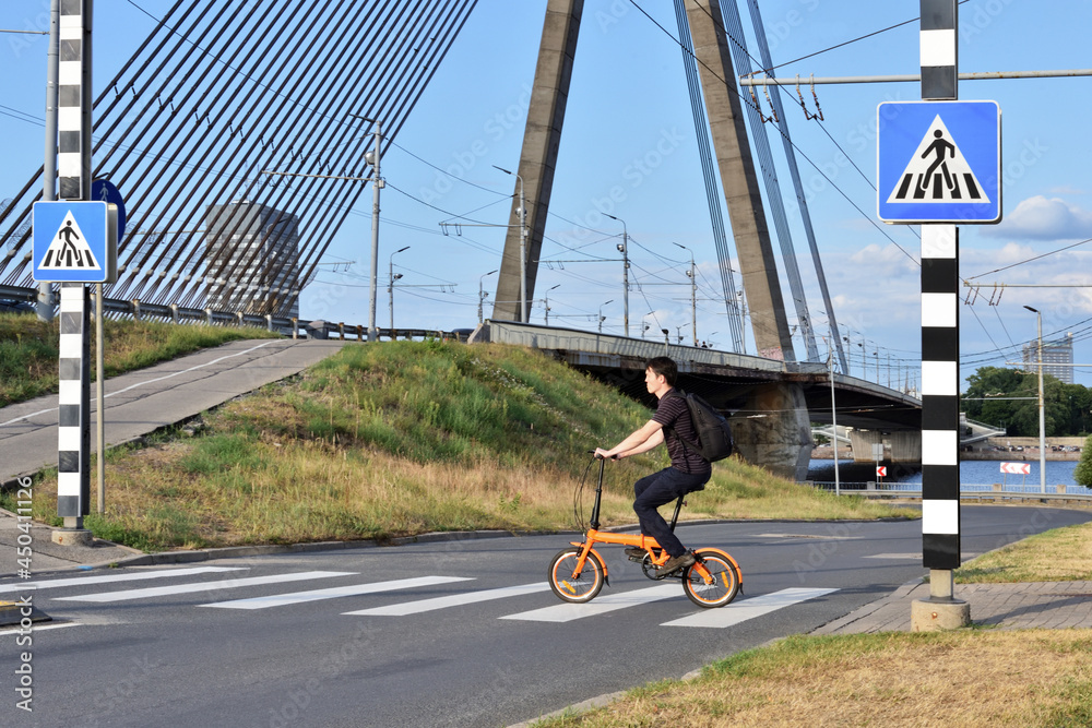 Cyclist crossing the roadway on a crosswalk. Equipped pedestrian ...