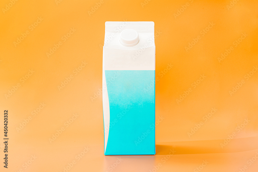 White and blue cardboard box of milk on a orange background. Eco food ...