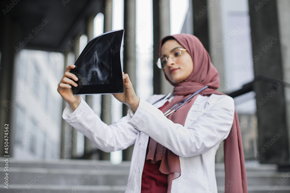 X-ray, roentgen image. serious thoughtful Muslim woman surgeon, looking ...