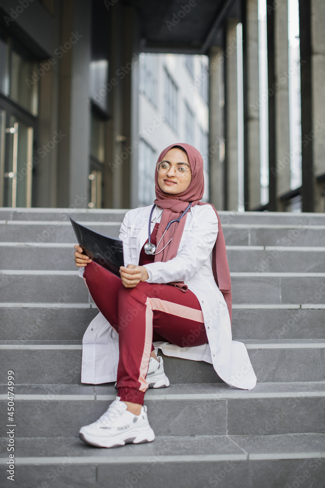Pretty muslim asian female medical doctor, wearing hijab, red scrubs ...