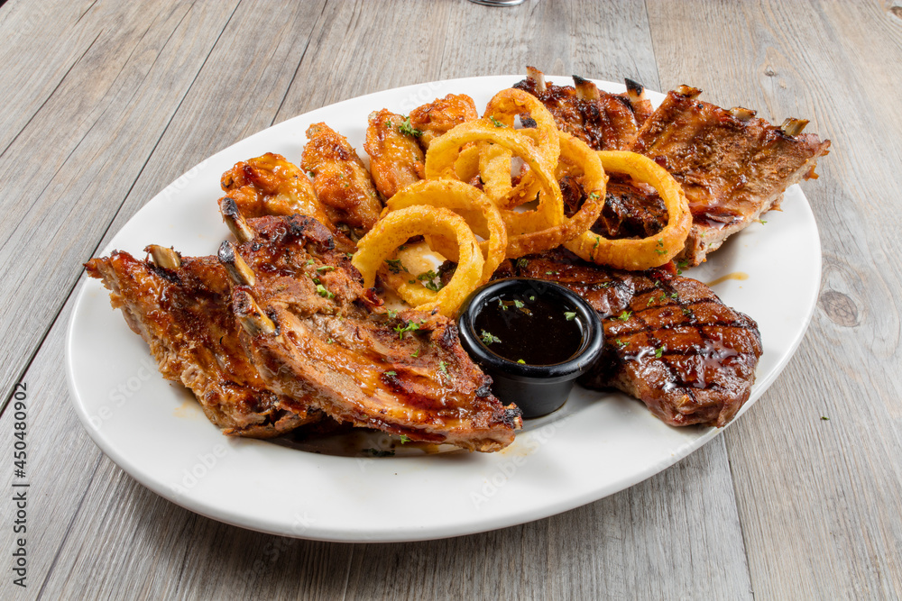 Costillar de cerdo, alitas de pollo, entrecot y aros de cebolla con ...