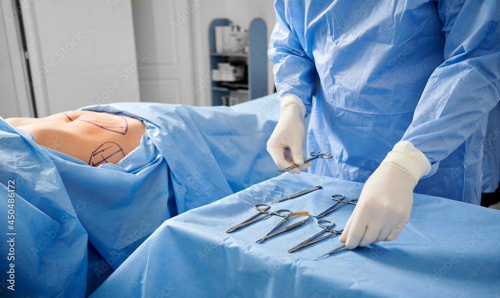 Surgeon in sterile gloves getting ready medical instruments. Patient ...