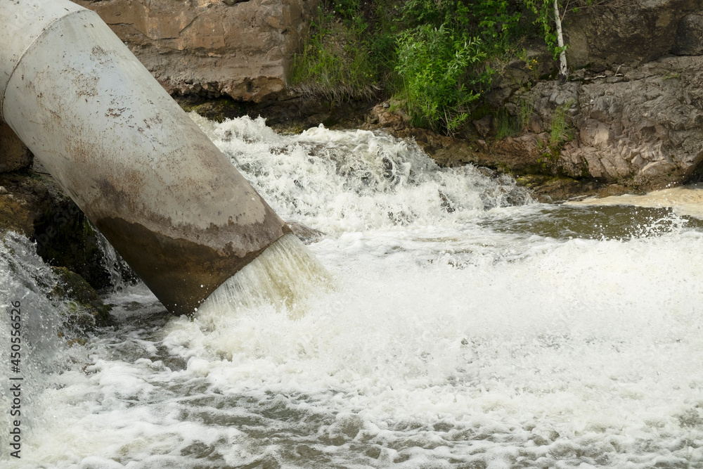 Dirty water and chemical waste are poured out of the pipe into a ...