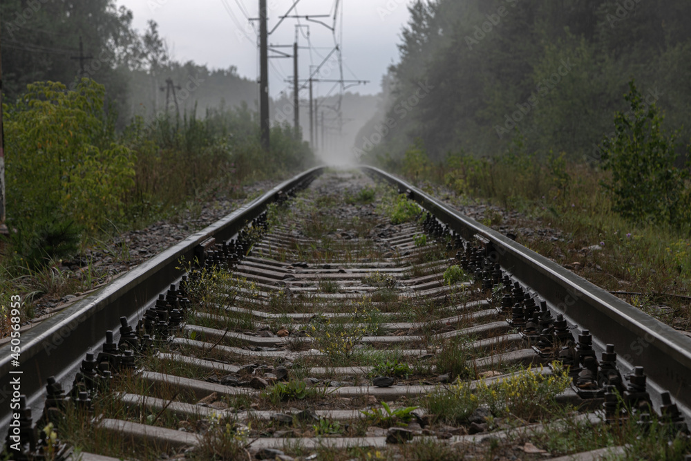 Gloomy photograph of a straight long railway. Rails receding and ...