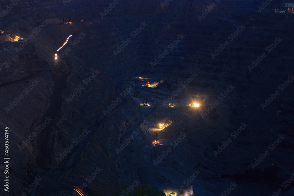 The process of ore extraction in the quarry at night. Heavy industry ...