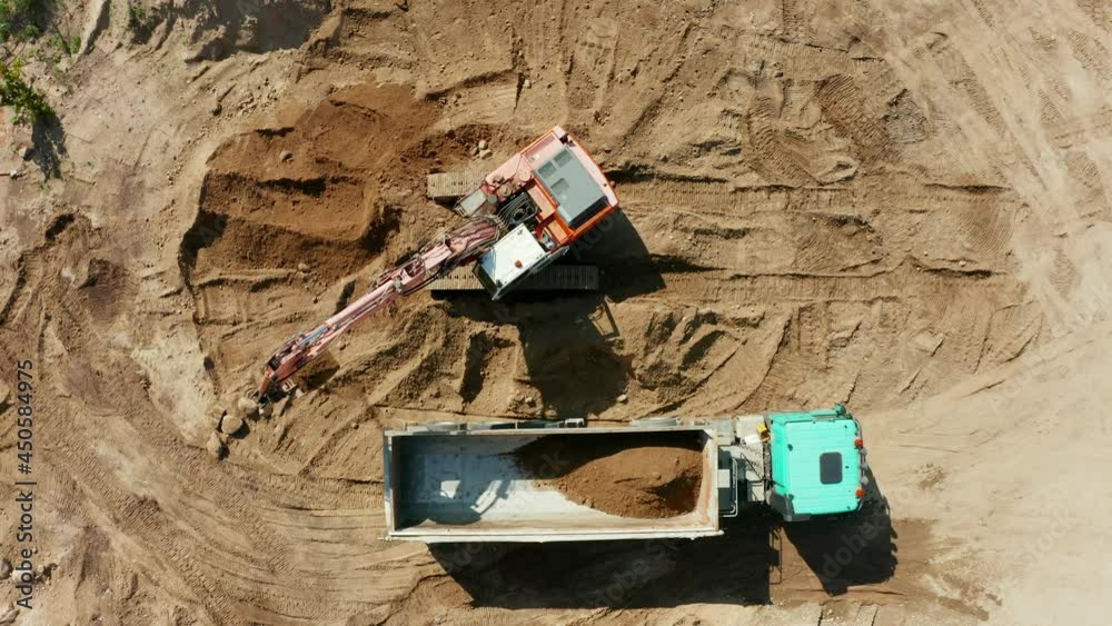 Construction site, top-down view of an excavator loading soil into a ...