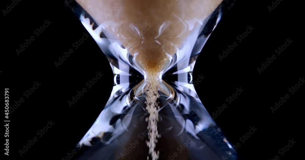 Hourglass. Sands move through hour glass. Sandglass close-up on a black ...