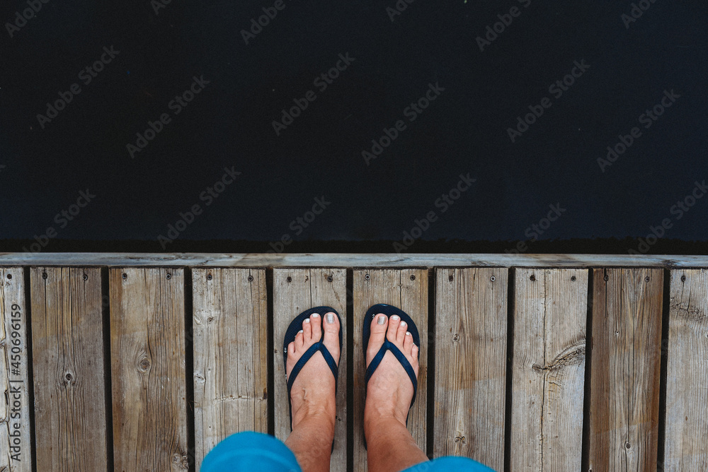 Overhead of woman's feet in flip flops standing on edge of dock. Stock ...