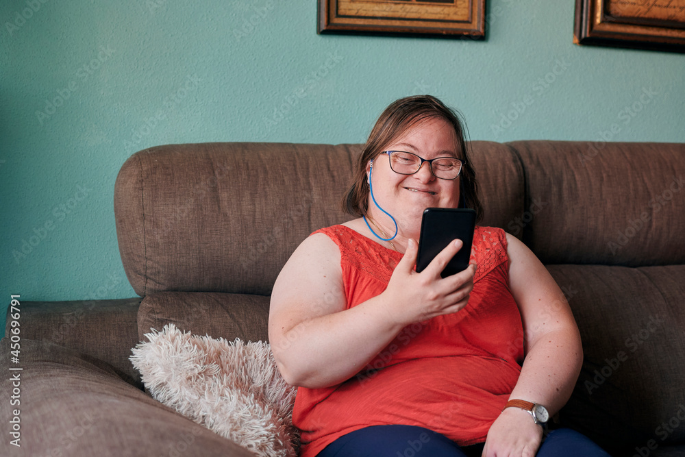 Adult woman with down syndrome smiles and looks her phone at home Stock ...
