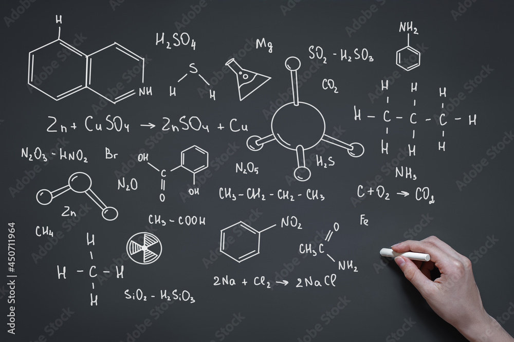 hand with chalk draws on the blackboard formulas and elements, signs ...