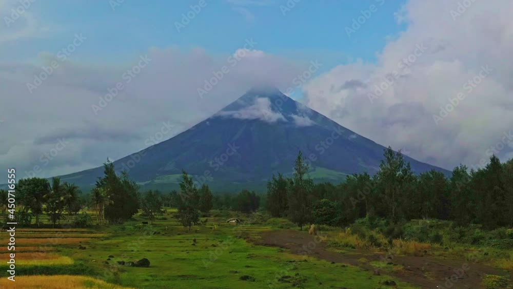 Mayon Volcano - the camera is flying low over the rice fields towards ...