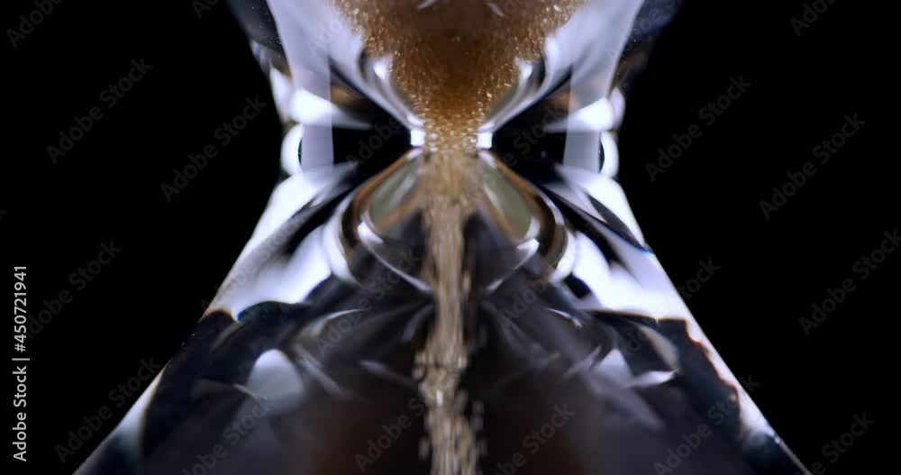 Hourglass. Sands move through hour glass. Sandglass close-up on a black ...