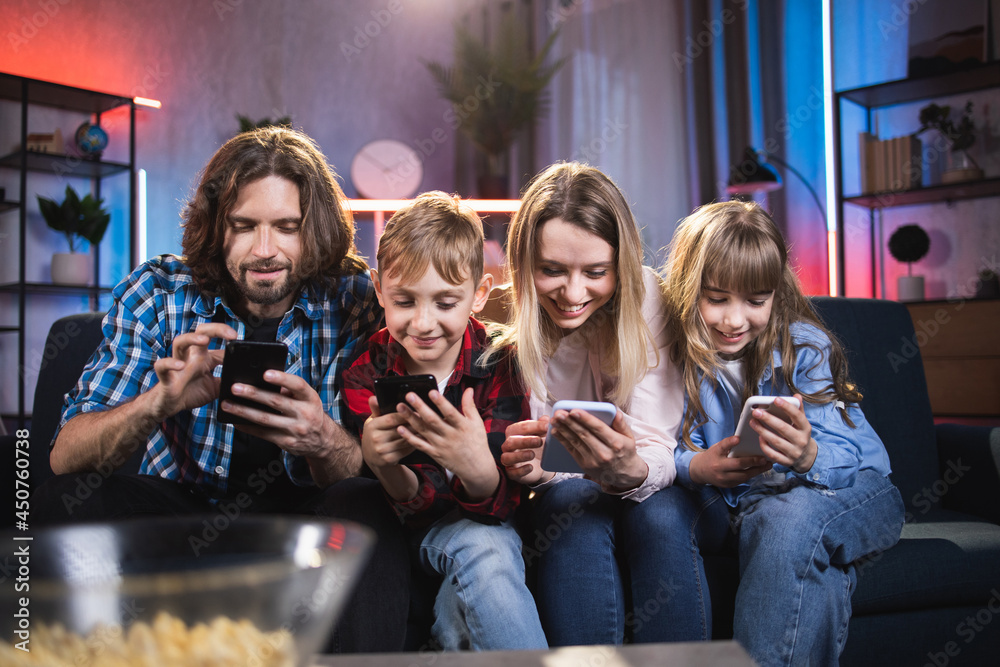 Two kids and their parents using personal smartphones while sitting on ...