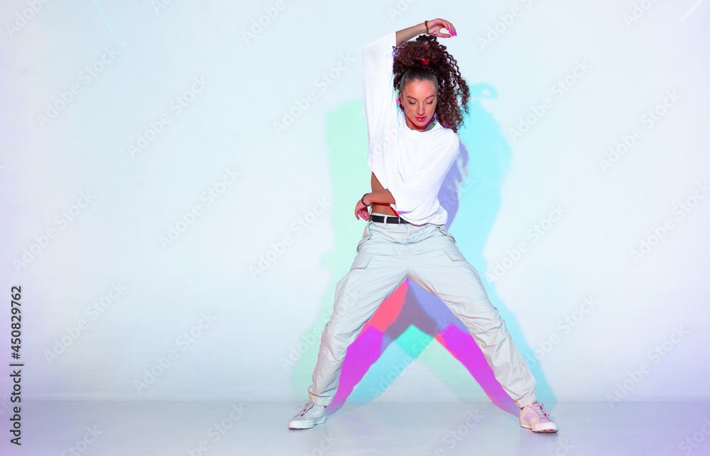 Dancing mixed race young girl in colourful studio light. Stylish female ...