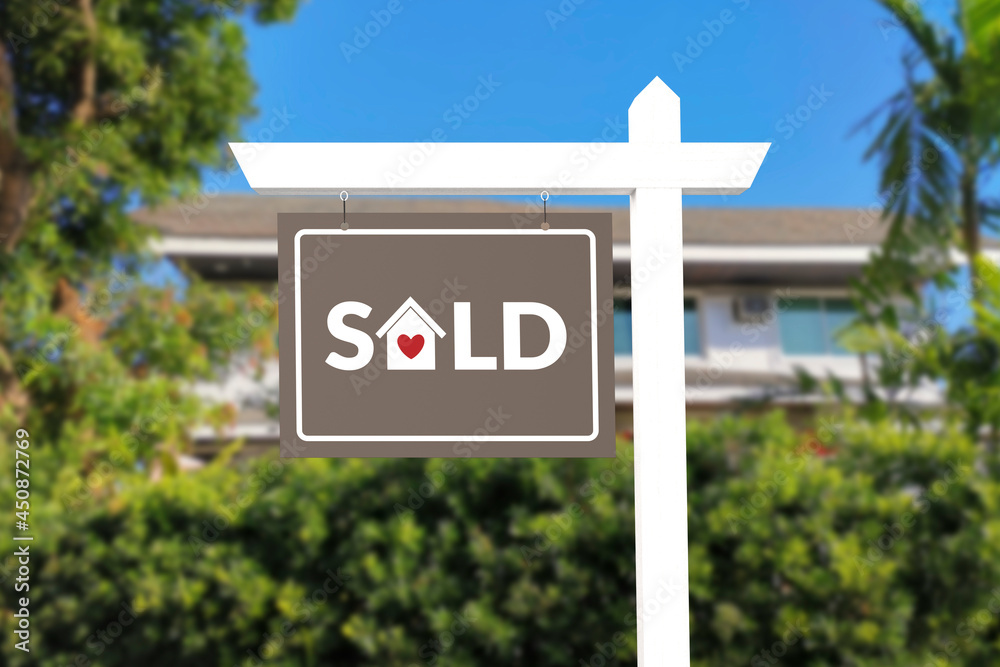A unique and cute sold sign in front of a luxury house with a hedge ...