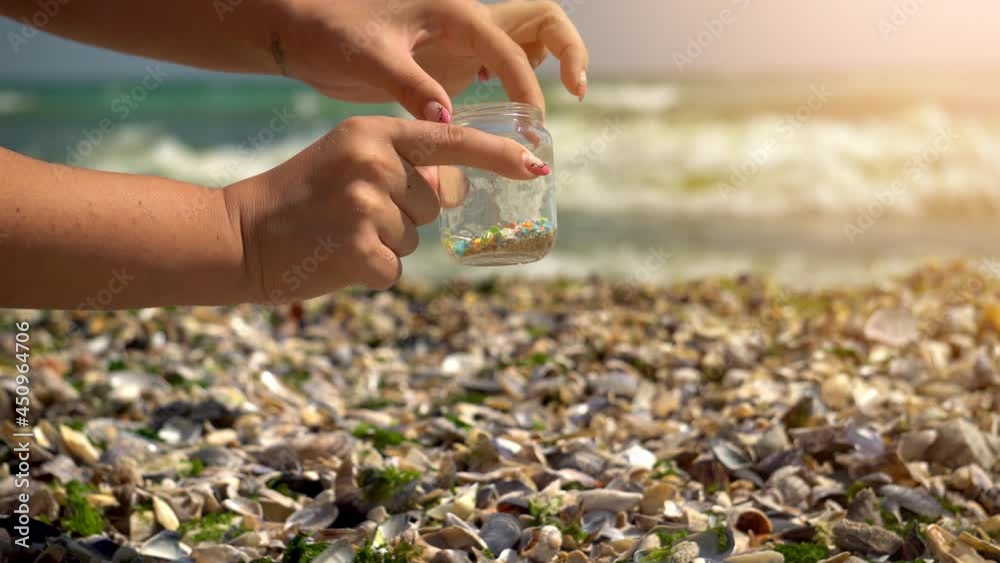 Close-up side view of a woman volunteer collecting microplastics from ...