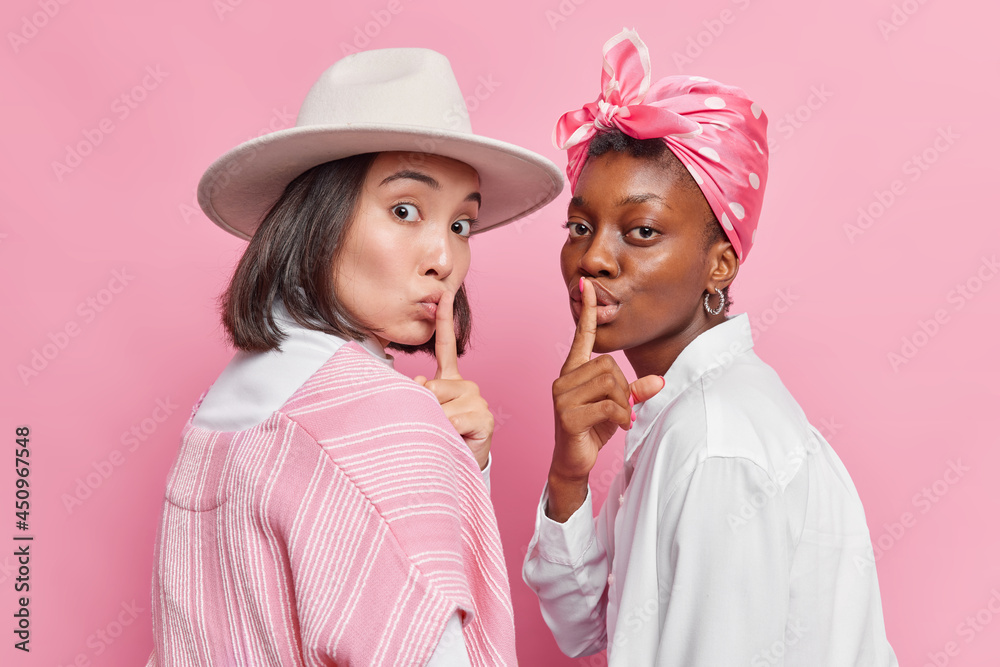 Diverse women look secretly at camera hide something ask to keep quiet ...