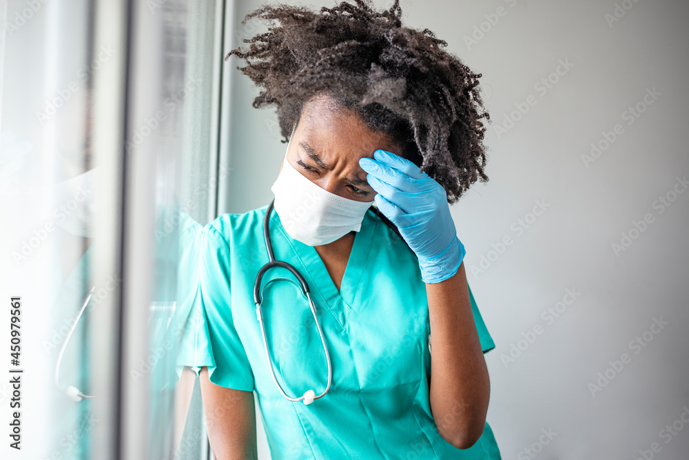 Overworked healthcare worker holding her head in pain at the hospital ...