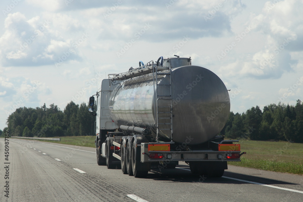 3 axle Gray barrel semi truck back side view on right lane move on ...
