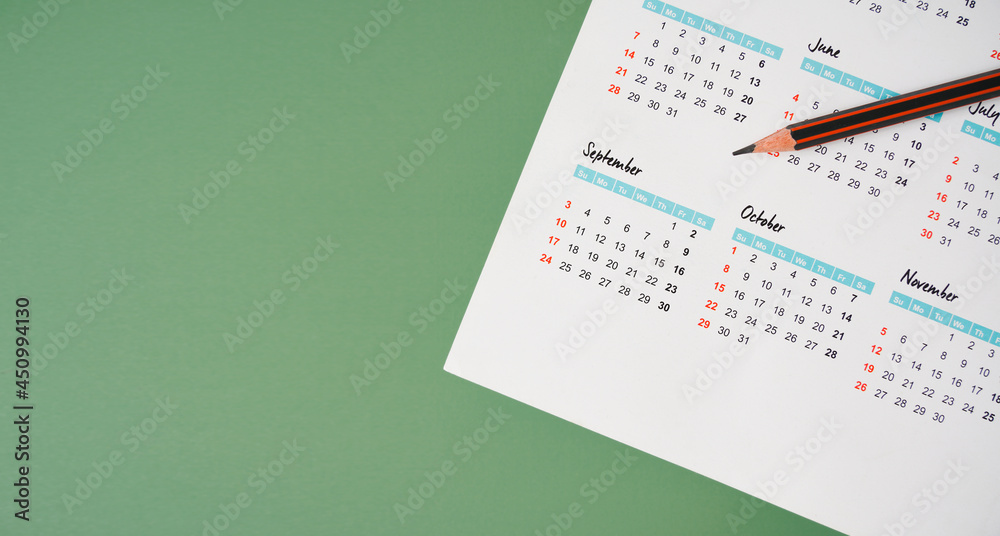 top view of pencil on white calendar and green background for planning ...