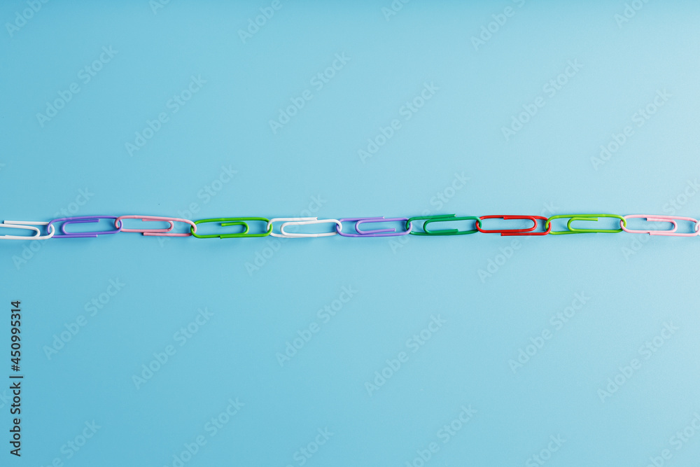 Interlocked colored paper clips in a line on a blue background with ...