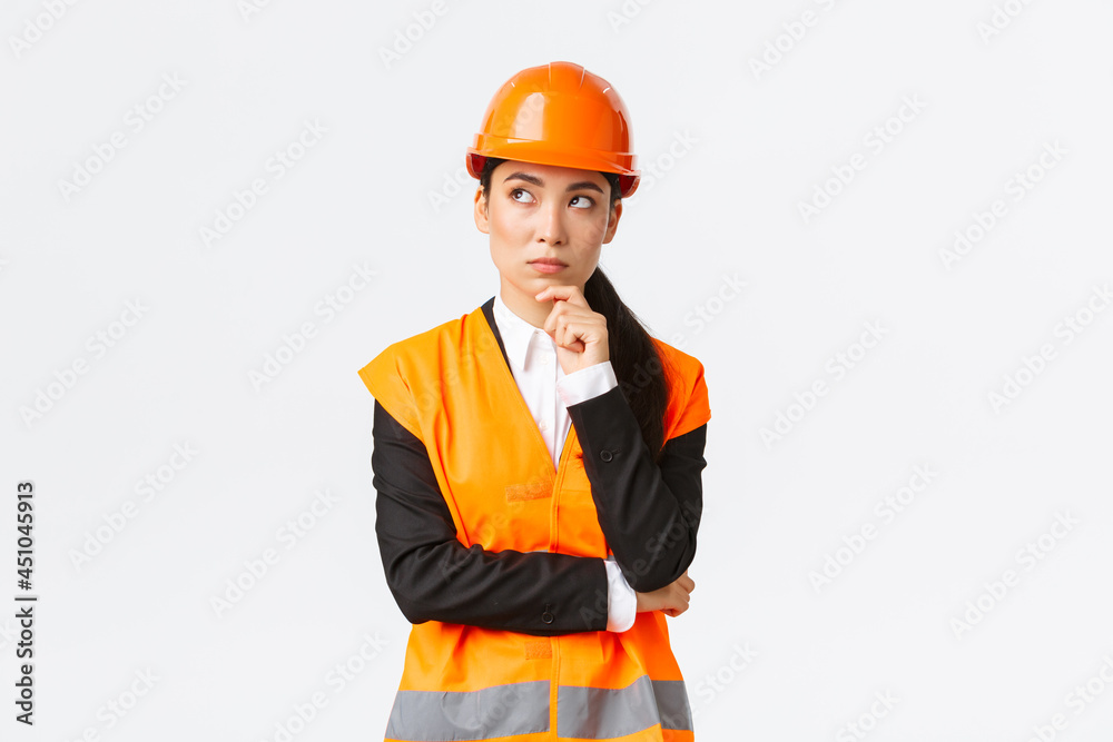 Thoughtful creative female asian engineer in safety helmet, reflective ...