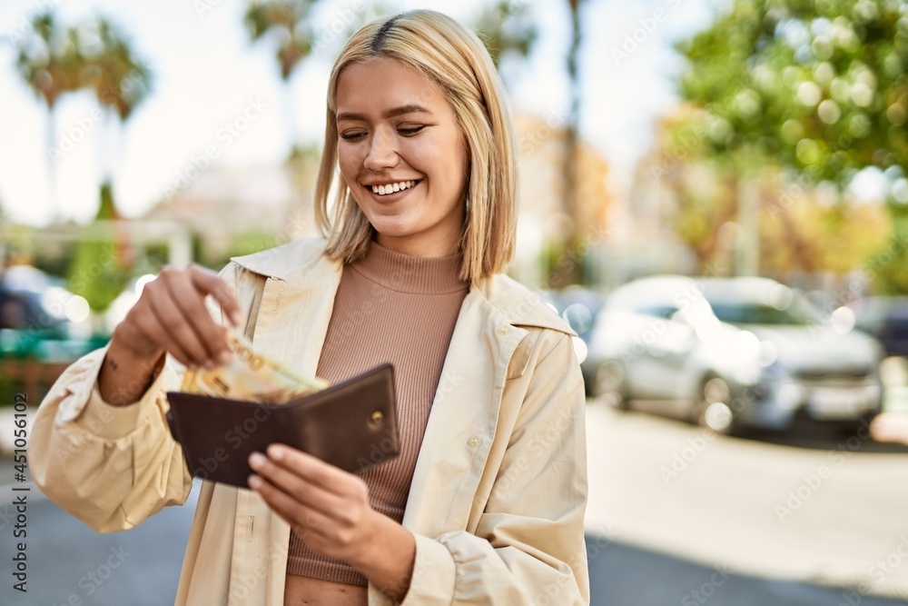 Young blonde girl smiling happy holding wallet with norway krone ...