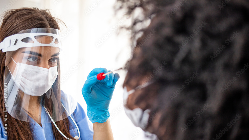 Close up of female health Professional in PPE introducing a nasal swab ...