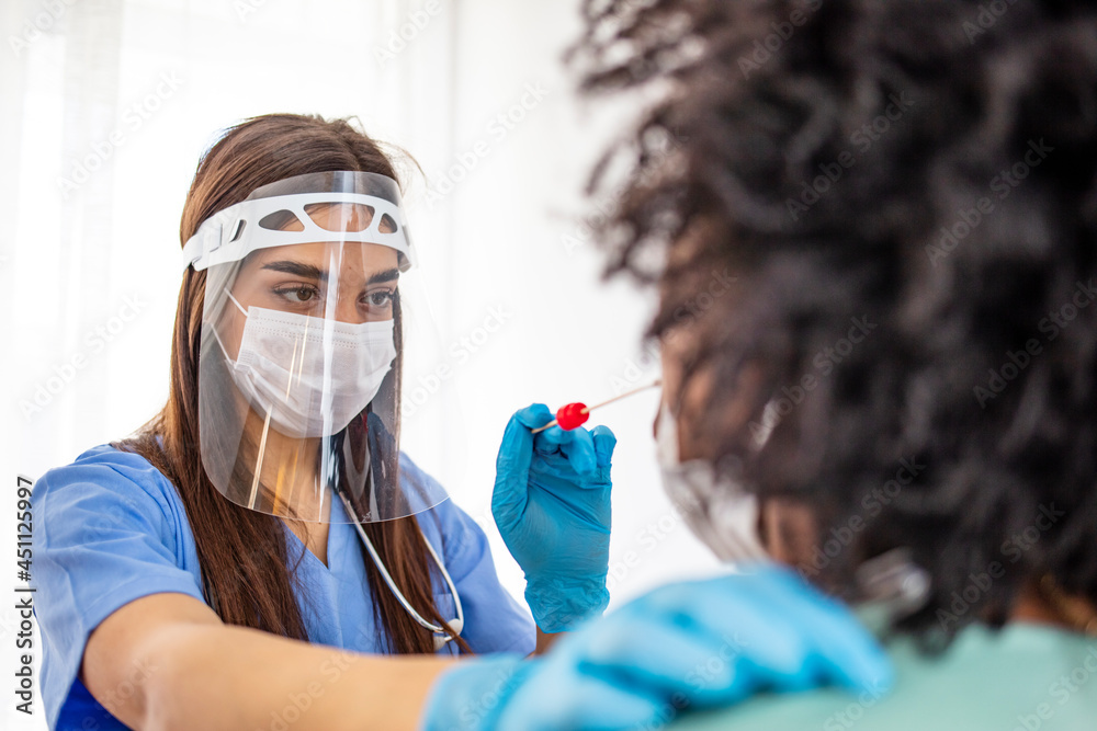 Close up of female health Professional in PPE introducing a nasal swab ...