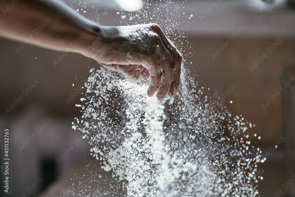 Glowing particles of flour in the air and a woman's hand close-up ...