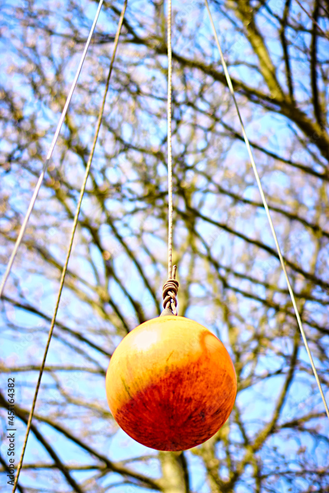 Orange rubber ball hanging in mid air suspended with rope. Tied with a ...