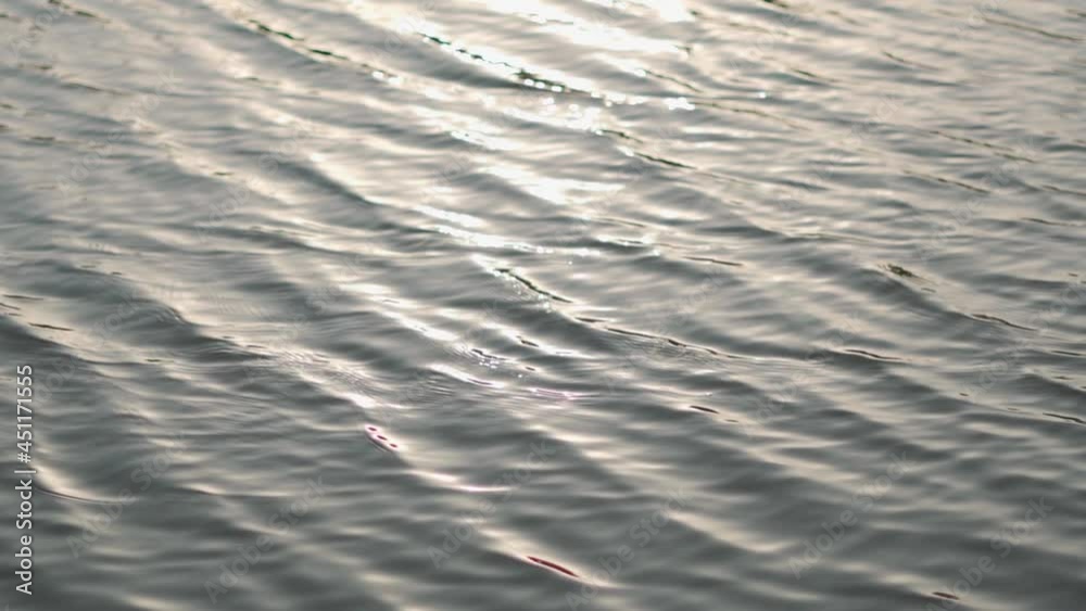 Rack focus shot of water ripples during the sunset. Water background ...
