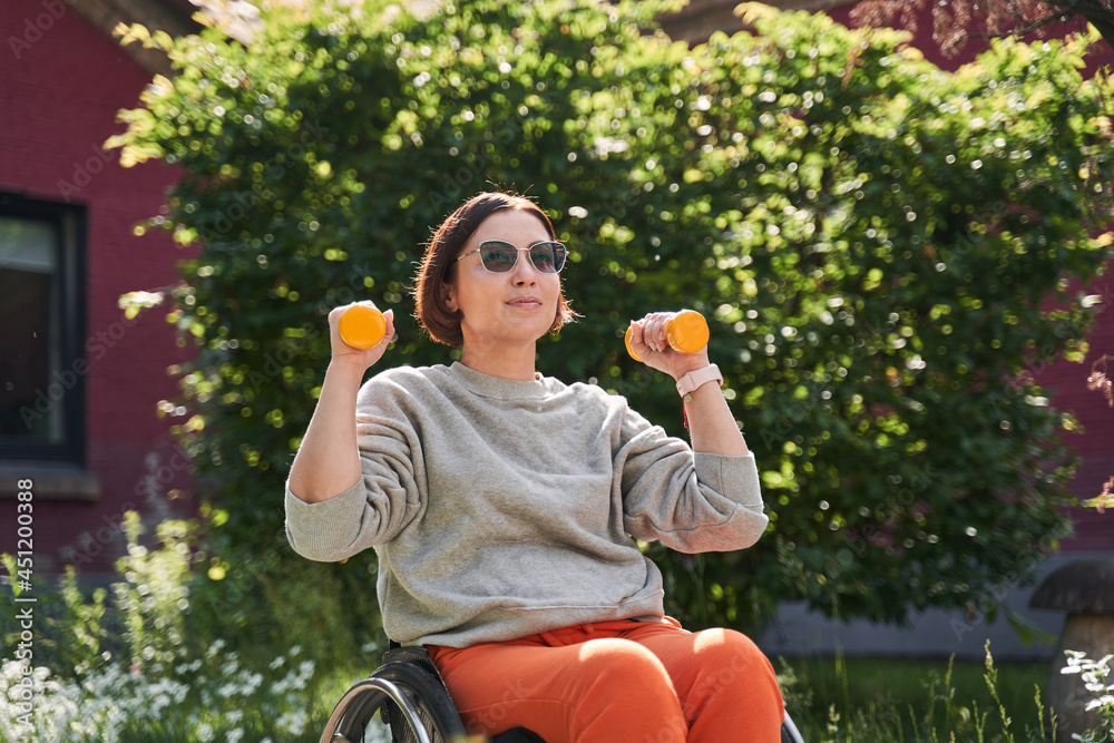 Girl with lower body disability holding dumbbells and exercising at the ...