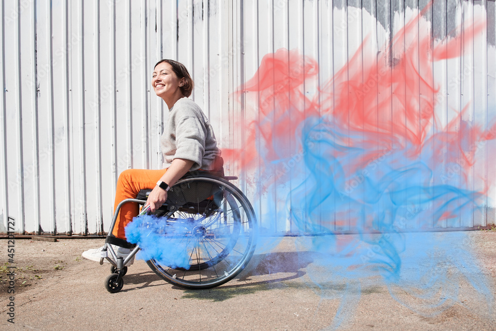 Woman with lower body disability riding at the wheelchair while holding ...