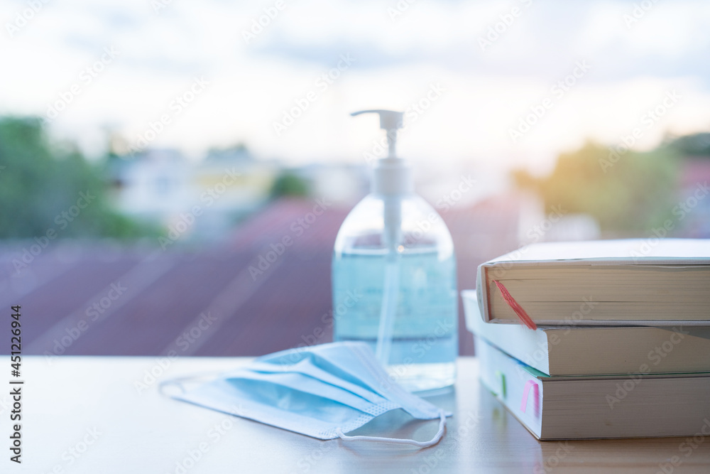 Stack of reading books with face mask and sanitizer liquid on the ...