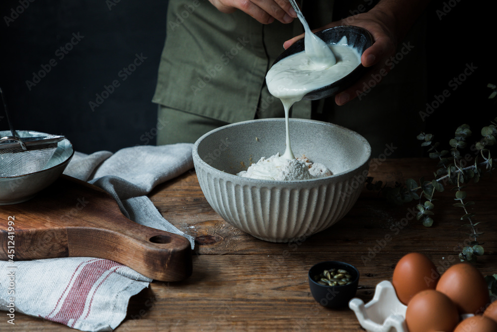 Crop cook adding yogurt to flour Stock Photo | Adobe Stock