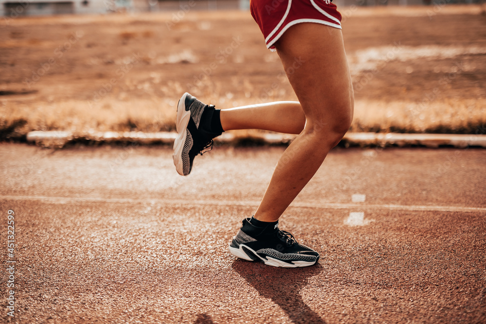 Feet of a female runner who is stepping on the running field with ...