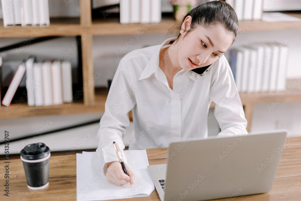 Pretty businesswoman sitting on the phone at her desk with laptop ...