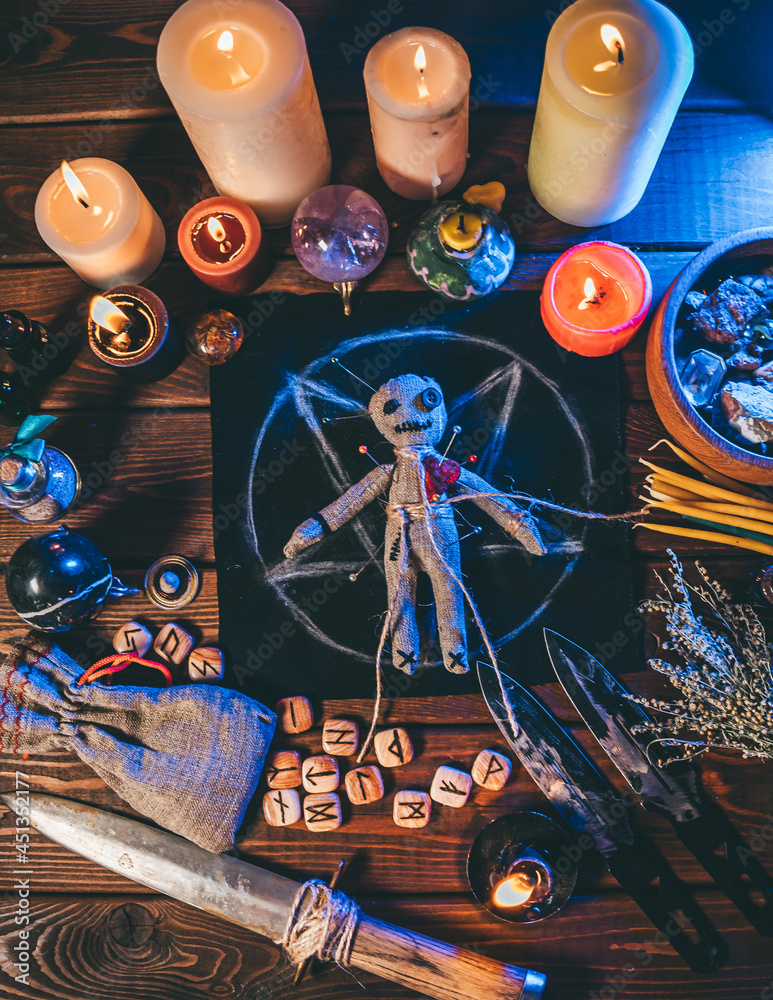 Voodoo doll on wooden table with candles and occult objects, top view ...