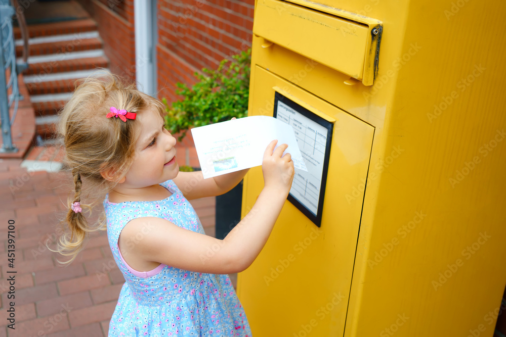 Little preschool girl throwing letter in a mailbox. Excited child ...