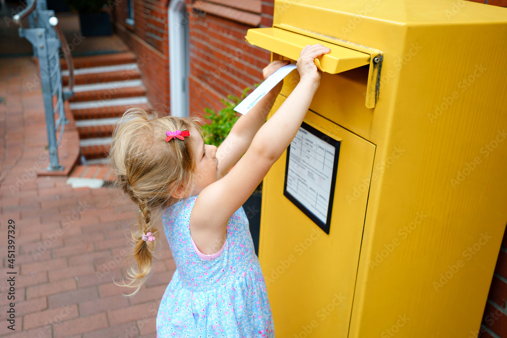 Little preschool girl throwing letter in a mailbox. Excited child ...