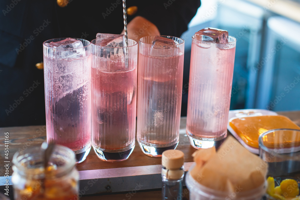 Bartender in front of beautiful row of different coloured alcohol ...