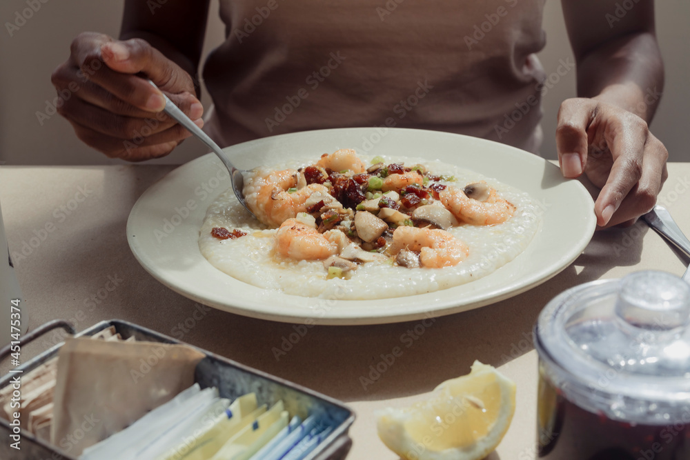 Person eating a bowl of shrimp and grits inside of a restaurant Stock ...