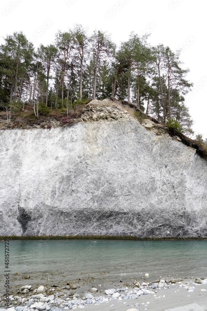 Rocky wall with coniferous trees above water level of Anterior Rhine ...