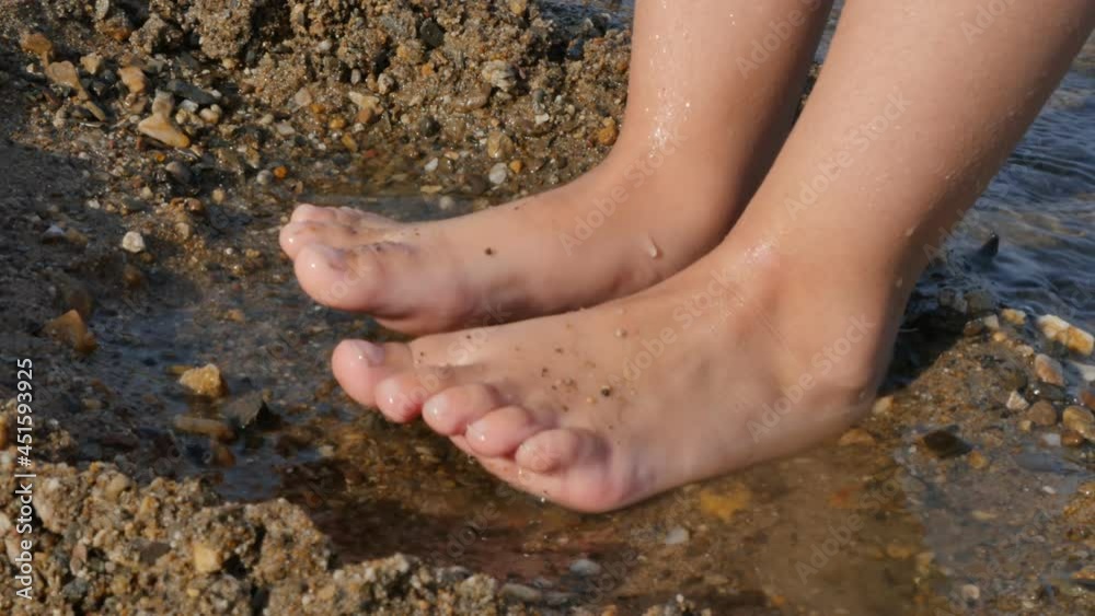 Vídeo do Stock: the bare feet of a child stomp in puddles of water on ...