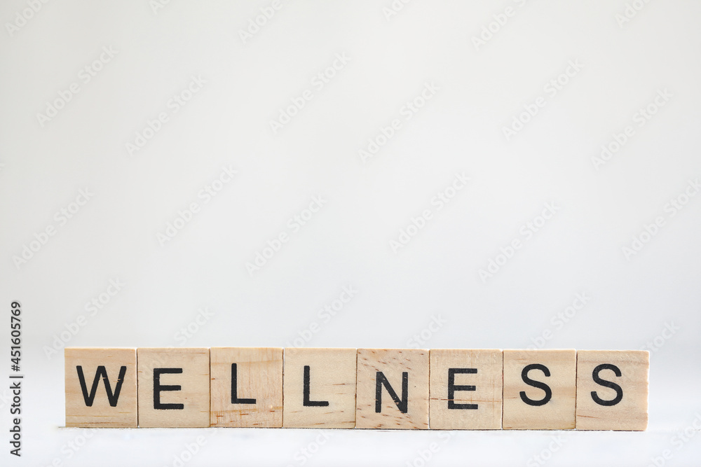 WELLNESS text in wooden block letters on plain white background with ...