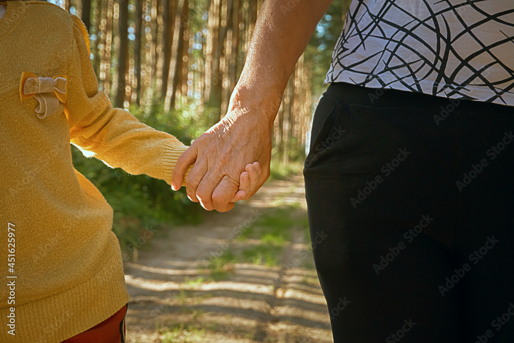 Two people hold hands, the older and younger generation of people ...