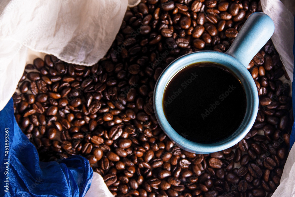 taza de café azul sobre granos de café en fondo de mármol con telas ...